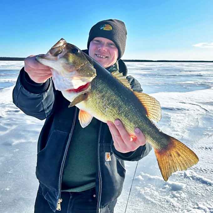 A proud angler displays his catch on the frozen lake, where the fishing stories get taller as the day gets colder.