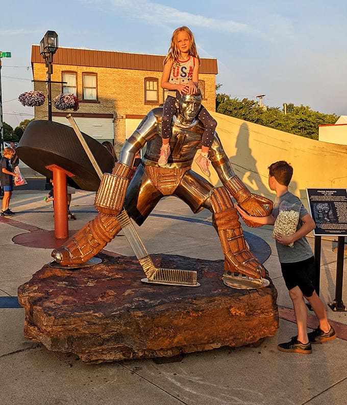 Young visitors discover the joy of standing next to something ridiculously oversized &ndash; childhood wonder meets hockey heritage in a perfect Minnesota moment.