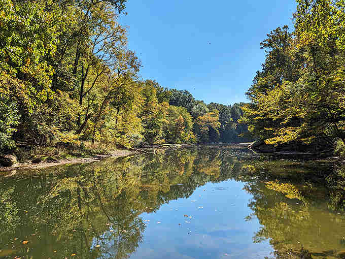 Golden hour perfection: Autumn sunlight dances across the tranquil waters, creating a mirror-like surface that doubles the seasonal color explosion.