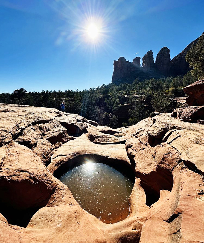Sunlight dances on the surface of a sacred pool, creating a mirror that reflects both sky and stone in perfect desert harmony.