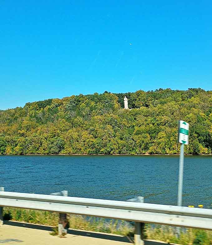 Glimpsed from the road, the statue appears to emerge mysteriously from the treetops, beckoning curious travelers to investigate.
