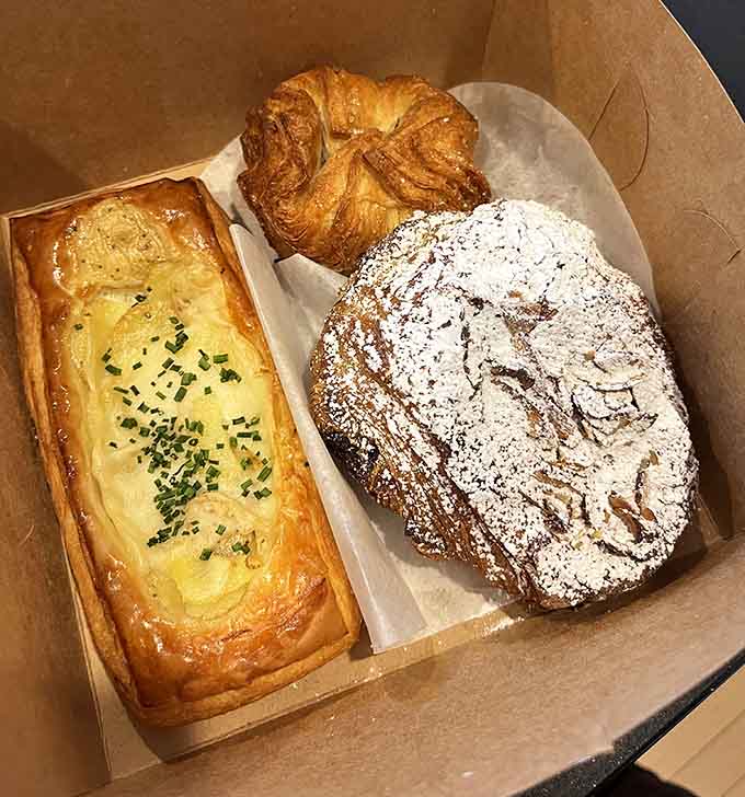 The pastry selection showcases technical skill and quality ingredients, from almond croissants to chocolate-dusted treats that demand attention.