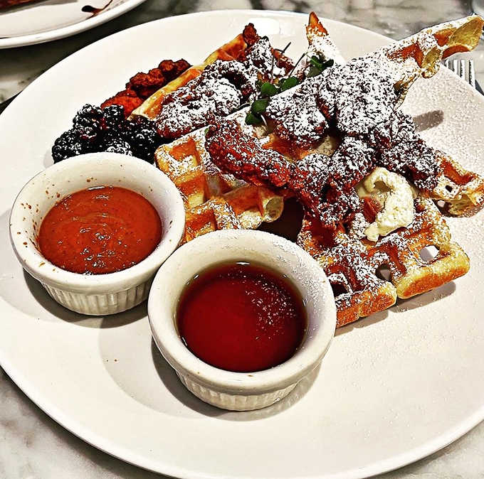 Weekend goals: golden waffles dusted with powdered sugar, fresh berries, and twin ramekins of maple syrup and house-made compote.