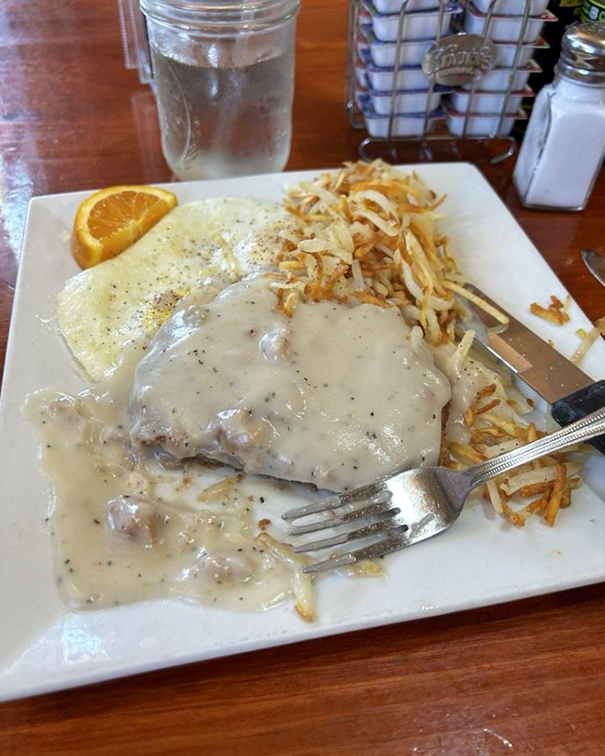 Country gravy cascades over tender meat like a delicious waterfall, while crispy hash browns stand ready to soak up every last drop of flavor.