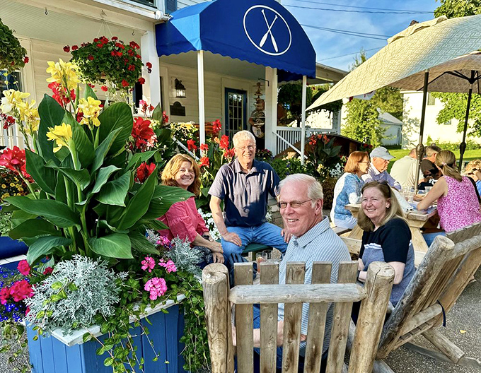 Happy diners surrounded by vibrant flowers create the perfect Vermont tableau, proof that good food creates its own special community.