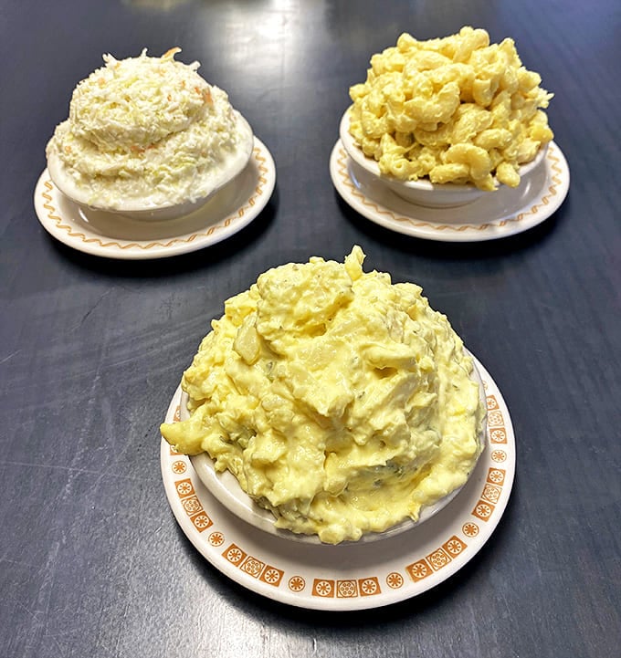Potato, macaroni, and coleslaw &ndash; the side dish trifecta made fresh daily by hands that understand the importance of proper seasoning.