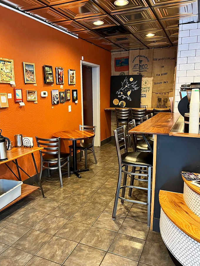 Vibrant orange walls adorned with local artwork create the perfect backdrop for your morning bagel ritual.