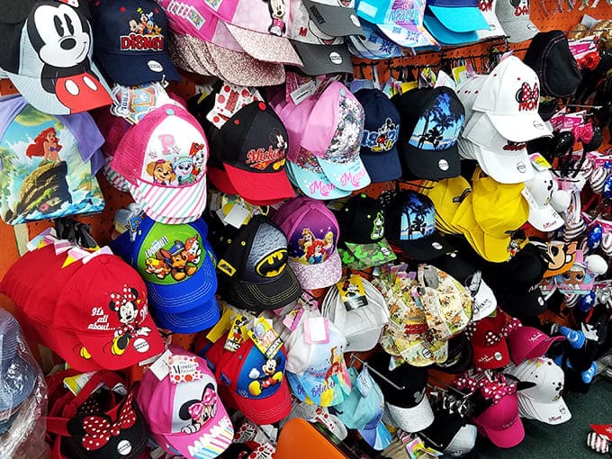 A kaleidoscope of character caps transforms ordinary tourists into walking billboards for their favorite Disney, Marvel and cartoon personalities.