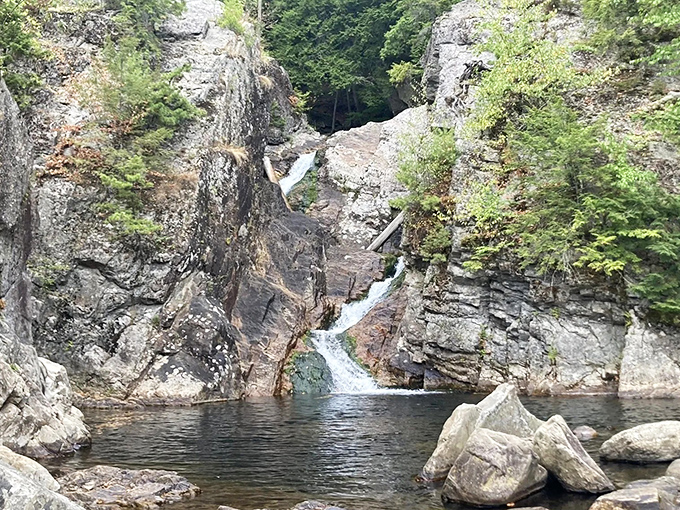 Cascading water gathers in a clear pool, creating Moosalamoo&rsquo;s refreshing natural escape carved into ancient rock.