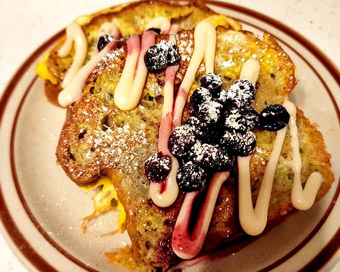 French toast that bridges breakfast and dessert, topped with fresh blueberries, powdered sugar, and sauces that make morning feel like a celebration.