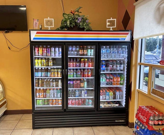 The beverage case stands ready like a colorful army of refreshment, offering liquid companions for your donut adventures.