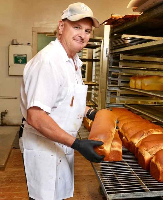 The friendly face behind these legendary baked goods, pulling fresh loaves with the confidence of someone who's mastered their craft.
