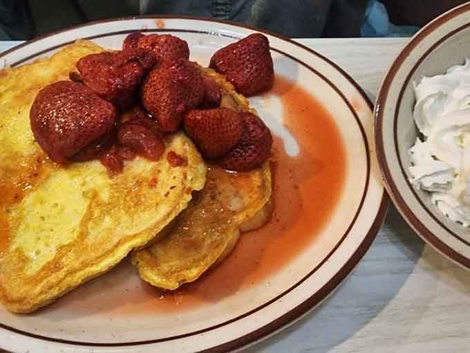 French toast with strawberries that transforms simple bread into something worthy of setting your alarm early, paired with whipped cream for good measure.