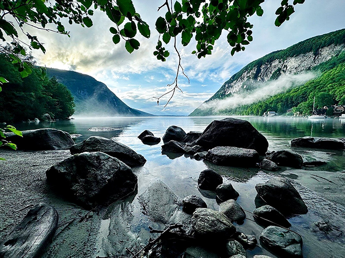 Morning mist performs its daily dance across the water, creating ethereal veils that drift between cliffs as loons call in the distance.