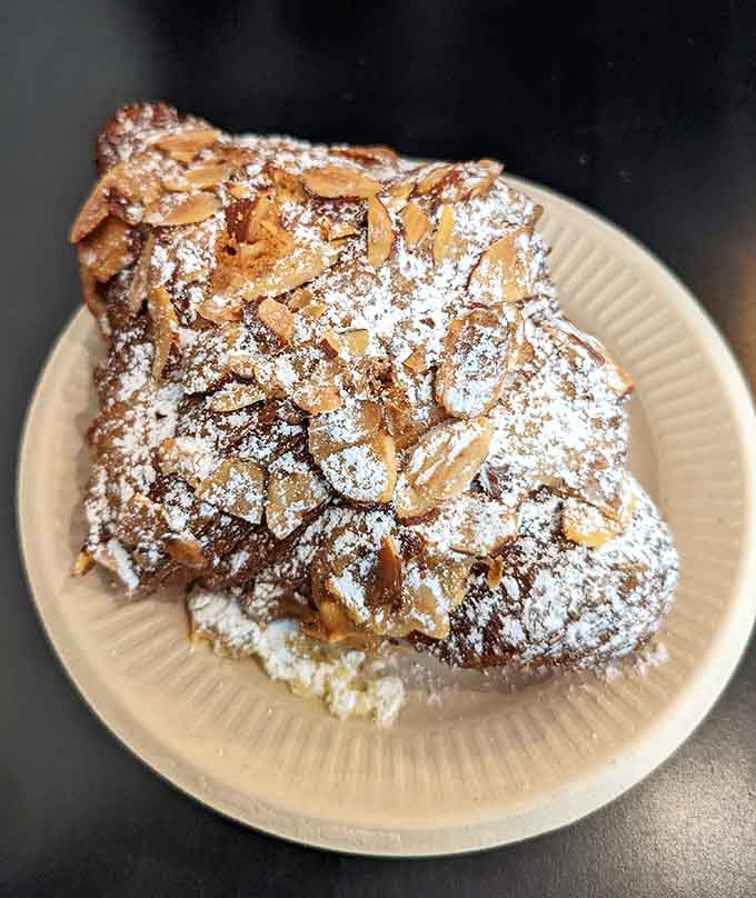 Sliced almonds crown this croissant like a delicious tiara, with powdered sugar adding just the right touch of sweetness.