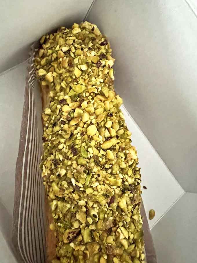 The pistachio &eacute;clair gleams with nutty promise&mdash;its elongated choux pastry shell filled with silky cream and crowned with crushed pistachios.