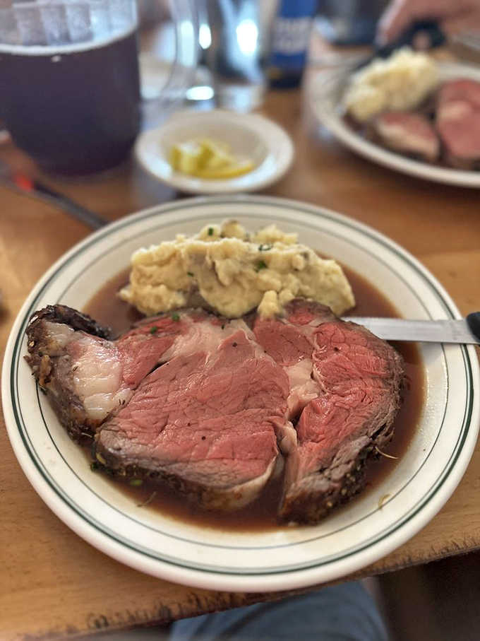 The prime rib arrives like royalty on a throne of mashed potatoes, its perfectly pink interior promising a flavor experience worth every mile of your journey.