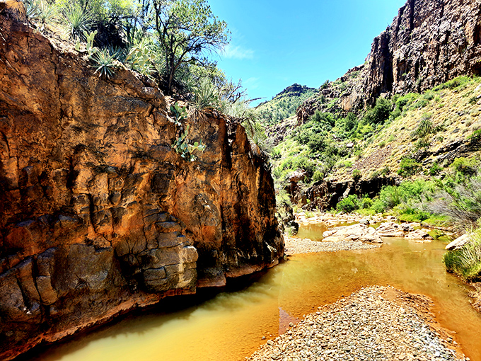 Canyon corridor: Sun-painted walls create a natural hallway of warm orange hues, guiding adventurers toward the sound of distant falling water.