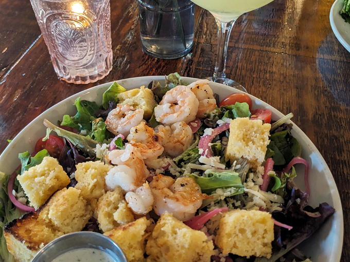 This isn't just a salad – it's a celebration of textures and flavors, where perfectly cooked shrimp meets fresh greens and homemade cornbread croutons.