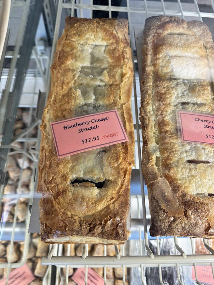 Flaky pastry architecture housing fruit treasures, like edible jewelry boxes where the gems are blueberries and cherries.