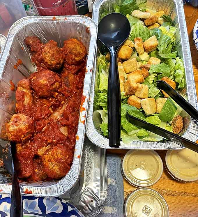 Meatballs swimming happily in homemade sauce alongside a Caesar salad pretending to make this meal "balanced."