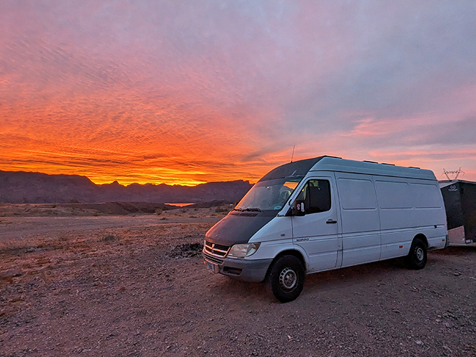 Mother Nature puts on her evening show as sunset paints the desert sky in impossible shades of orange and pink, silhouetting a visitor's van.