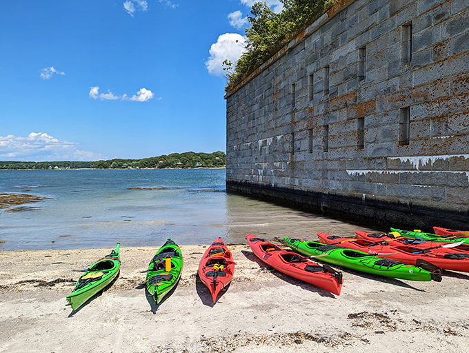 Colorful kayaks rest on the small beach, the modern adventurer's preferred method for reaching this isolated historic treasure.
