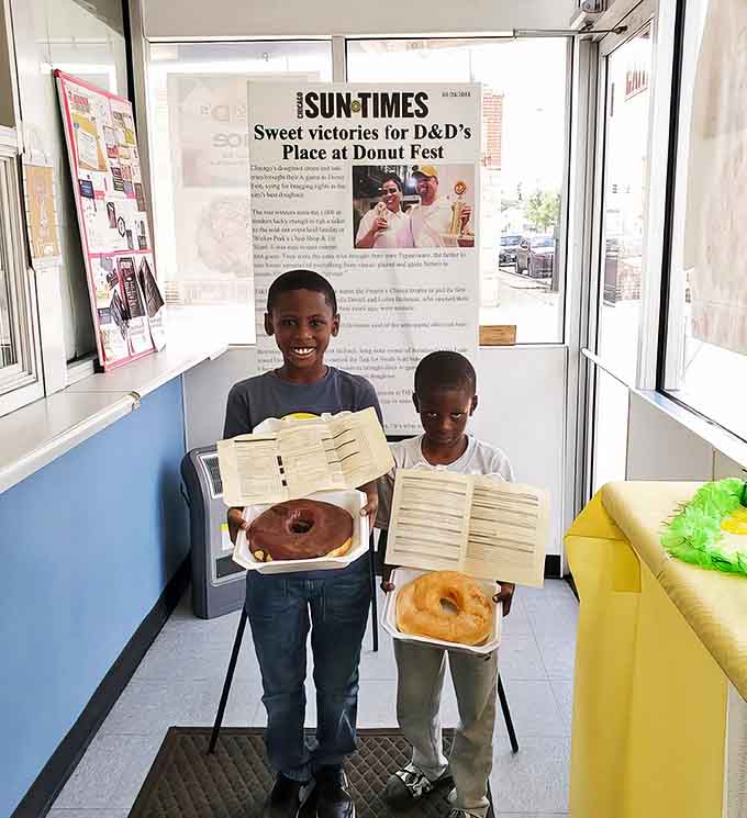 Young customers proudly display their donut treasures, proving that appreciation for a perfect pastry transcends generations at this beloved Chicago institution.
