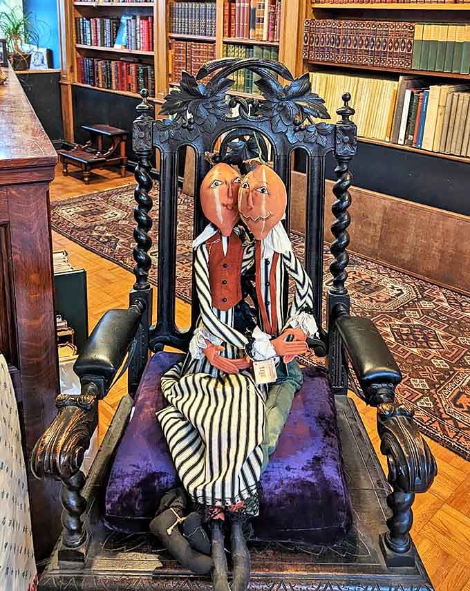 This ornate wooden throne featuring peculiar pumpkin-headed figures serves as both functional seating and a conversation-starting art piece.