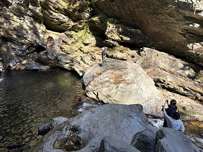 Hikers navigate the rocky descent to the falls, where each step brings them closer to Vermont's hidden aquatic treasure.