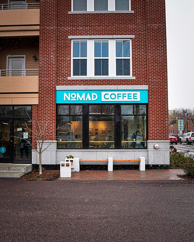 Nomad Coffee's bright turquoise sign promises caffeinated salvation to weary travelers and locals alike, a beacon of hope in brick form.