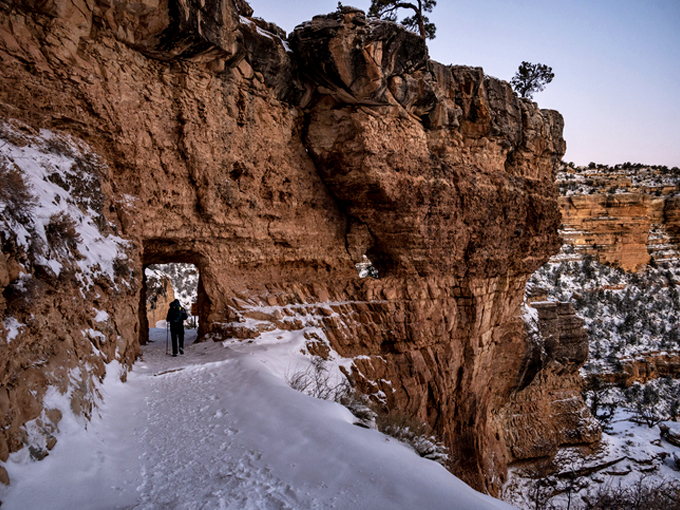 hiker passing through snow covered tunnel along bright angel trail
