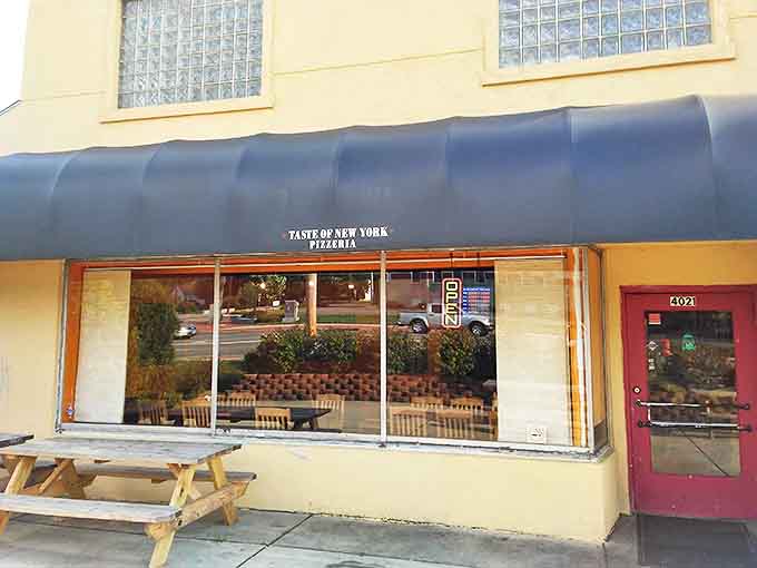 The unassuming yellow building with navy awning might not catch your eye, but locals know this modest exterior hides culinary treasures worth discovering.