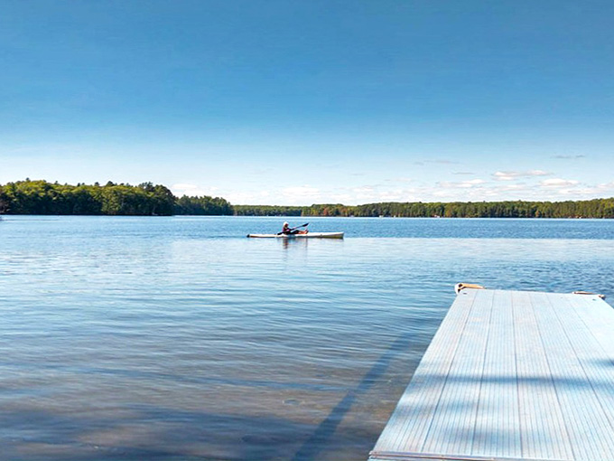 Black Oak Lake's crystal waters stretch toward the horizon, where a lone kayaker glides across nature's mirror.