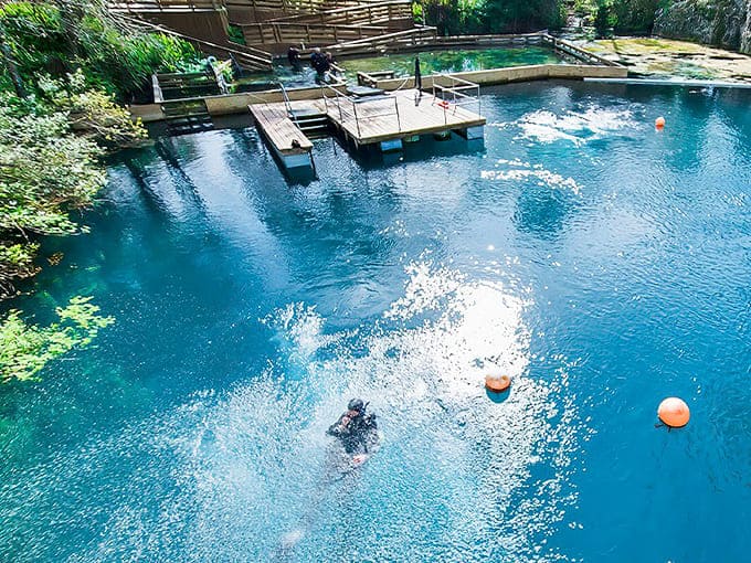 Nature's swimming pool beckons with crystalline blue waters, where divers explore depths while sunlight dances through the limestone cavern.