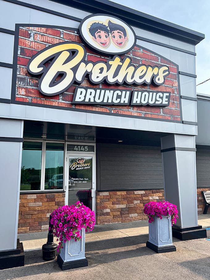 Welcoming storefront with vibrant pink petunias framing the entrance &ndash; a colorful invitation to the culinary treasures waiting inside.
