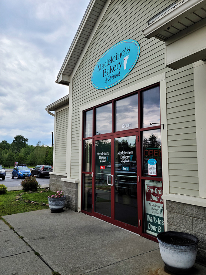 The welcoming facade of Madeleine's Bakery invites you in with its charming blue sign and promise of sweet treasures within.