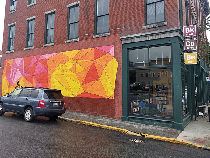 The vibrant geometric mural outside Elements Books Coffee Beer serves as a colorful beacon for literary and culinary adventurers in downtown Biddeford.