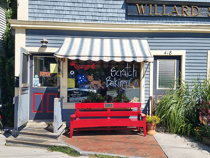 The charming blue exterior of Scratch Baking Co., with its inviting red bench, looks like the kind of place where carb-based happiness is guaranteed daily.