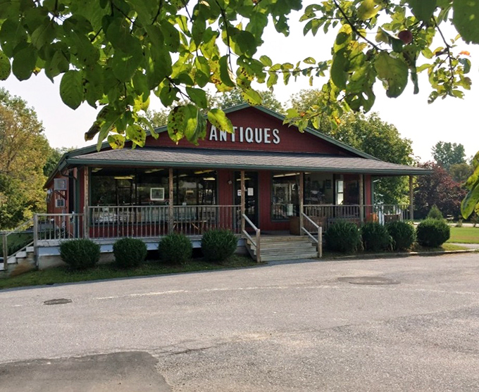 The welcoming red exterior of Champlain Valley Antique Center beckons treasure hunters with its wraparound porch and vintage charm &ndash; Vermont's time capsule awaits!