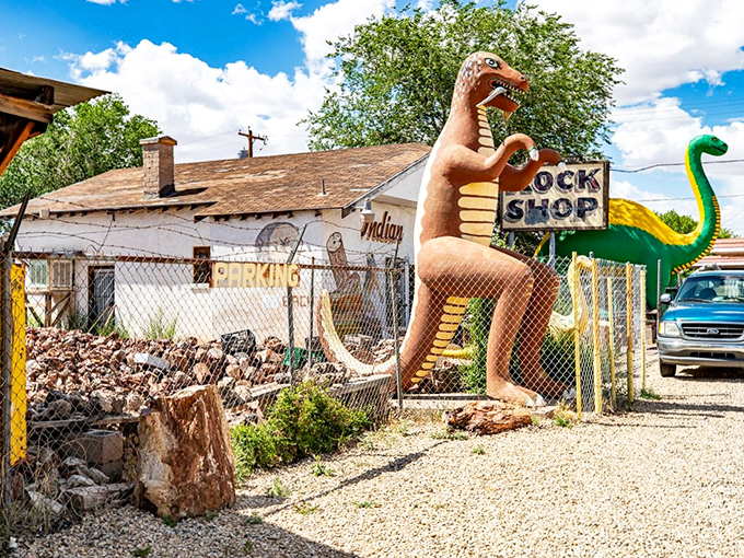 Prehistoric meets kitsch at Rainbow Rock Shop's entrance, where a towering dinosaur guards geological treasures within.