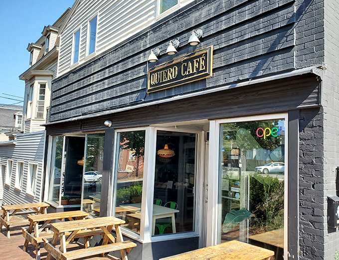 The sleek black exterior of Quiero Caf&eacute; stands out like a delicious secret waiting to be discovered, complete with inviting wooden picnic tables for al fresco dining.