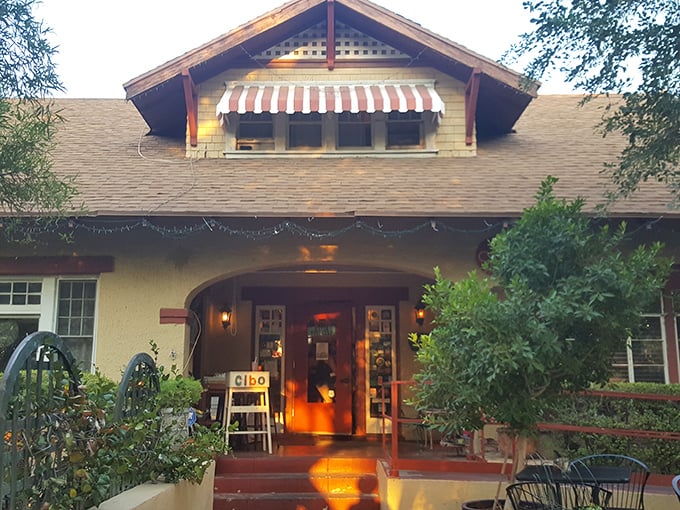 Exterior: A charming 1913 yellow bungalow with red trim and striped awnings beckons you into what might be Phoenix's most inviting Italian hideaway.