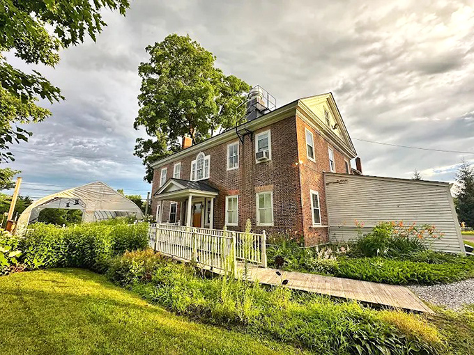 The historic brick farmhouse stands proudly against Vermont's sky, promising culinary magic within its walls. A rainbow seems to approve.