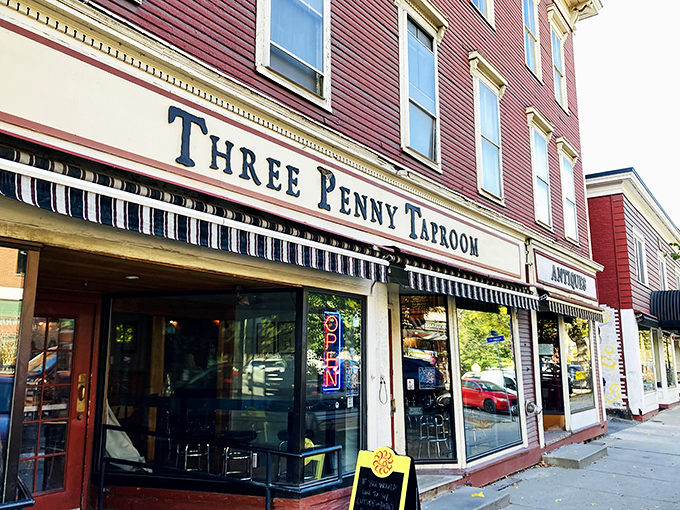 The classic red exterior of Three Penny Taproom beckons from Montpelier's charming streetscape, promising treasures within for the culinary adventurer.