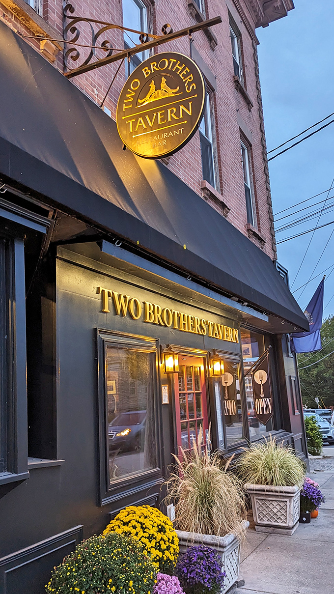 The glowing sign of Two Brothers Tavern beckons like a lighthouse for hungry travelers, promising comfort and satisfaction just beyond that red door.