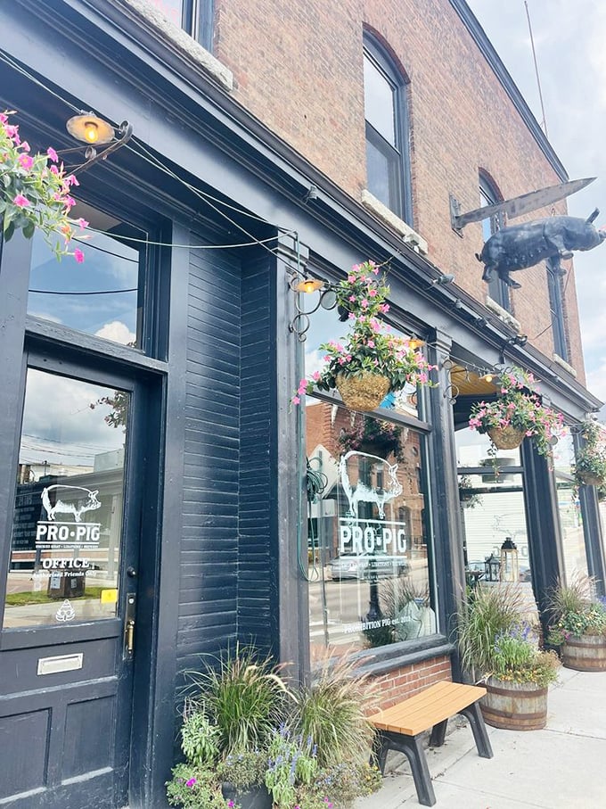 The historic brick exterior of Pro Pig welcomes hungry visitors with its distinctive flying pig sign and colorful hanging flower baskets.