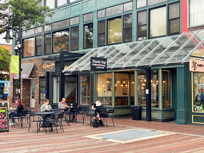 Black Cap Coffee & Bakery's welcoming storefront on Burlington's Church Street invites passersby with its charming glass awning and cozy outdoor seating.