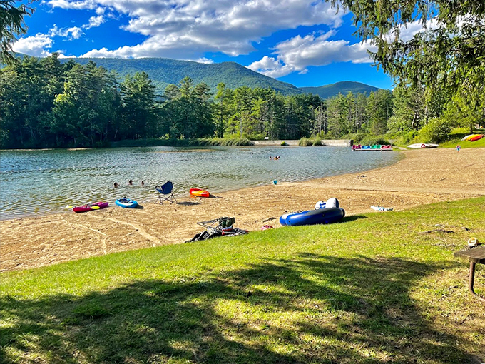 A pristine beach meets crystal-clear waters, with towering mountains as nature's backdrop. Summer perfection in Vermont's hidden paradise.