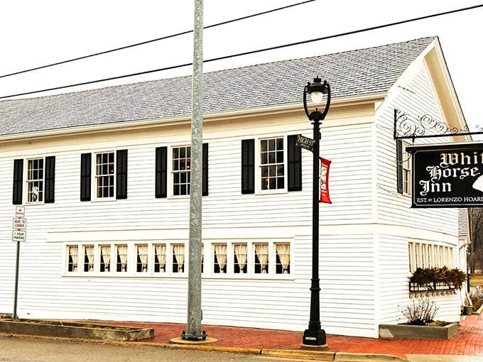 Classic white clapboard with black shutters, the White Horse Inn stands like a pristine historical landmark, promising timeless comfort within its walls.